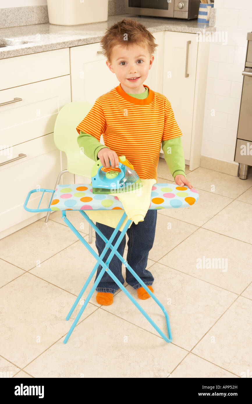 a boy plays in a kitchen with a toy ironing set Stock Photo - Alamy