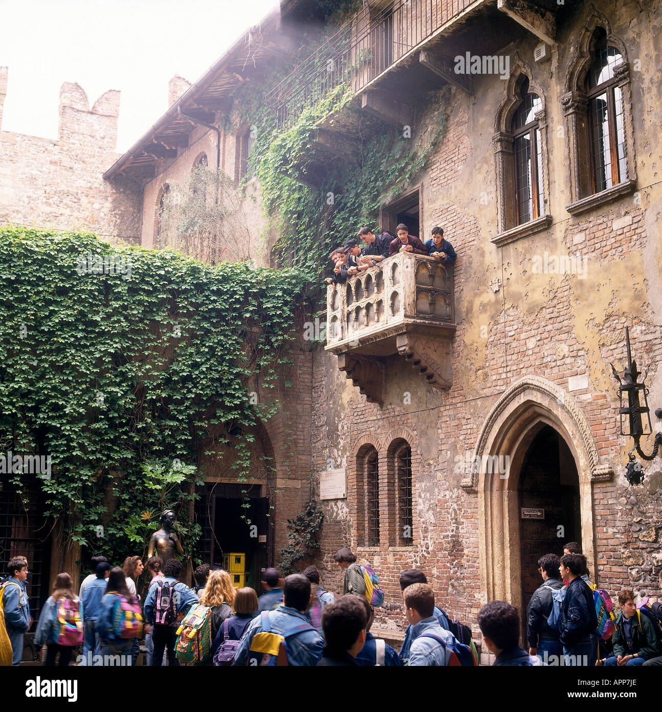 People in the courtyard enclosed by tall ivy clad walls looking up ...