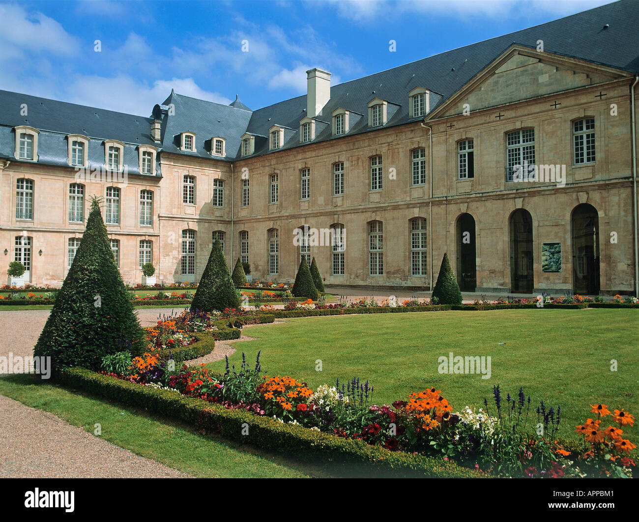 Neatly timmed shrubs and colourful flower borders in the courtyard of ...