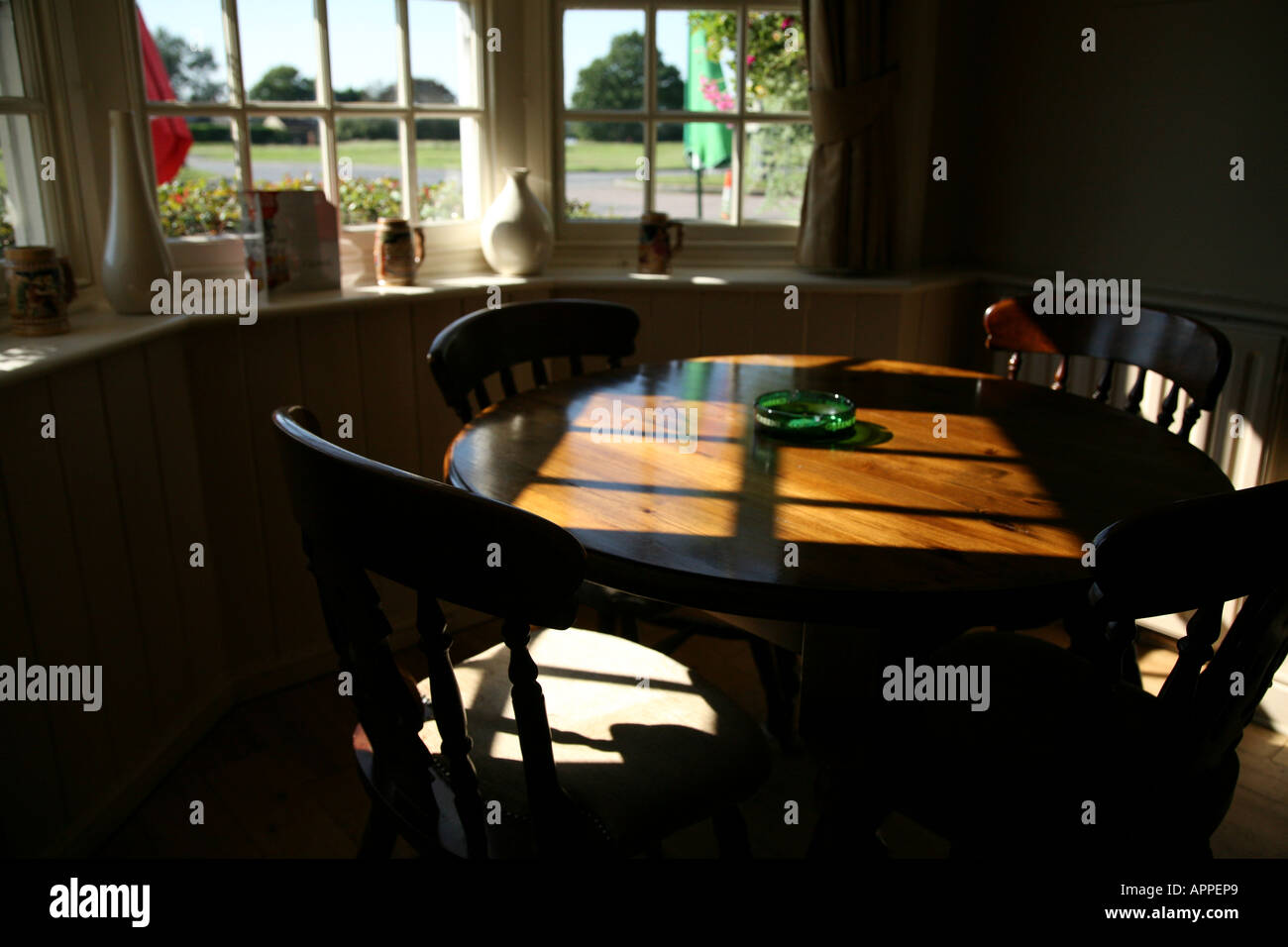Light shinning through a window onto a round wooden table in a room in ...