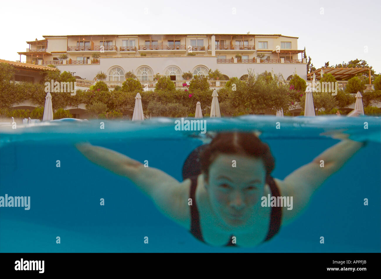 Hotel with woman underwater in pool split view above and below water ...