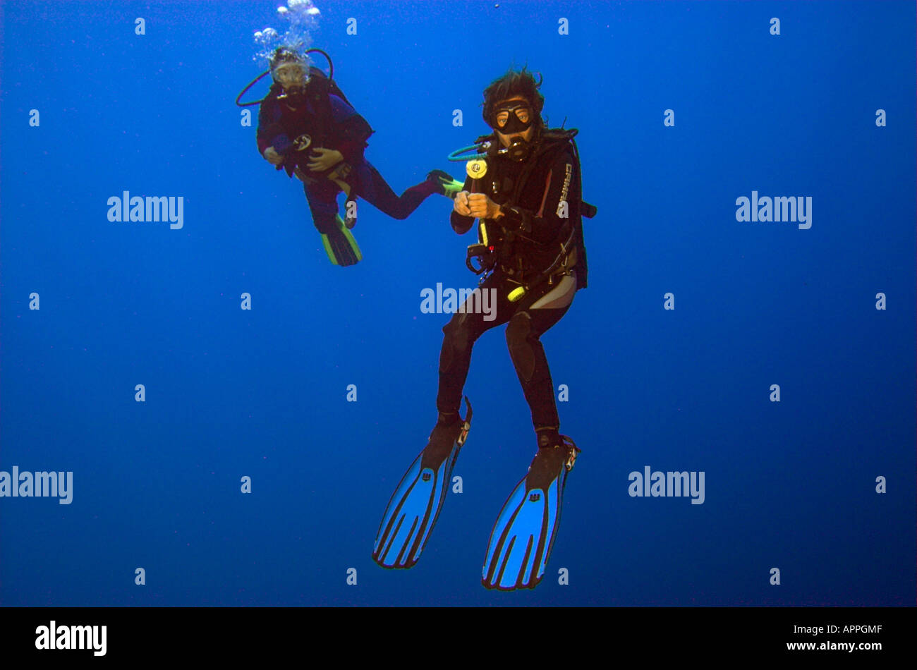 Looking up at two scuba divers in the clear blue underwater world Crete ...