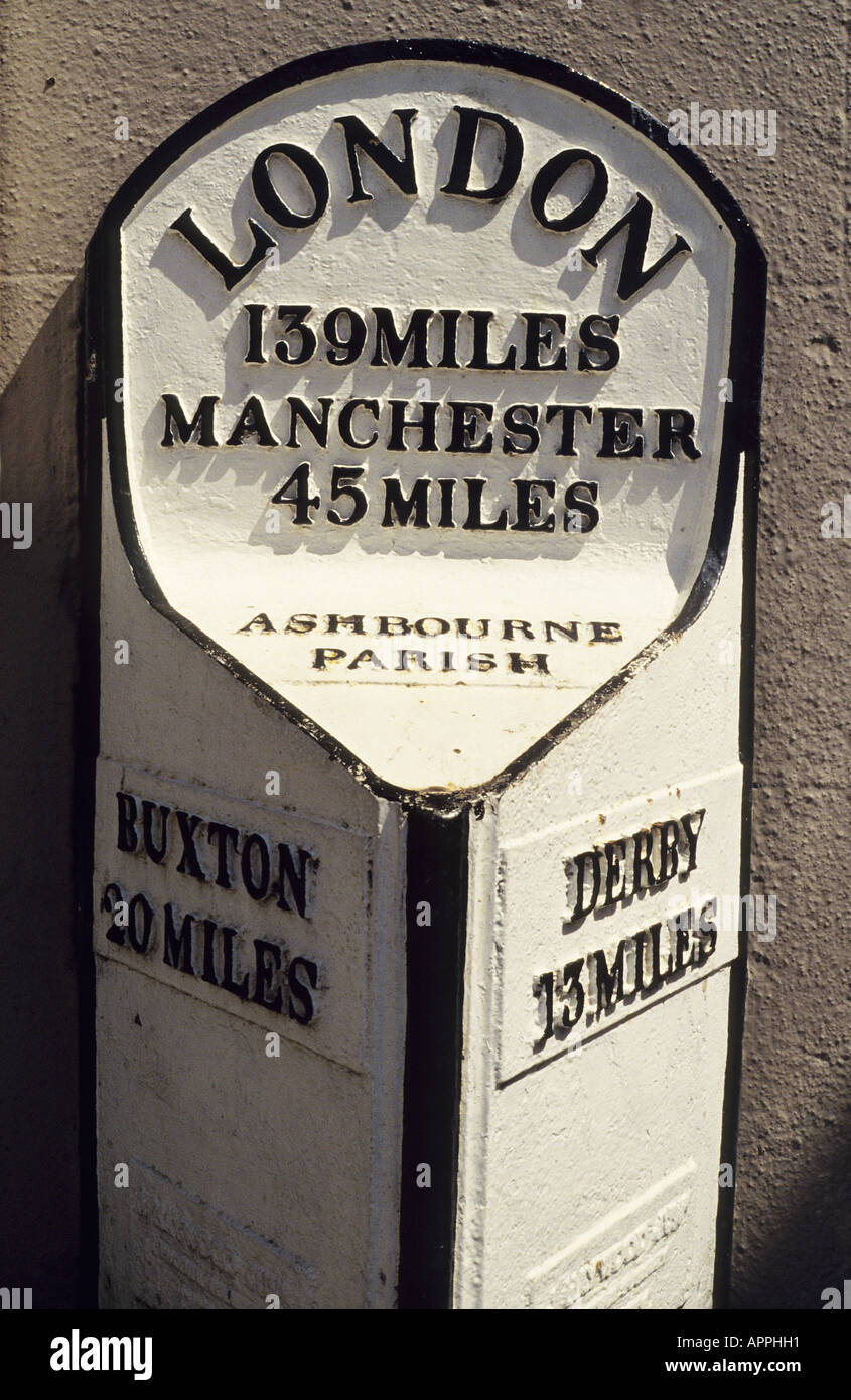 A black and white painted road sign displaying distances to London ...
