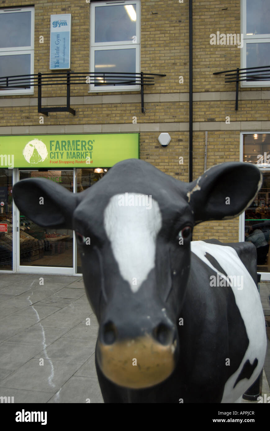 a cow statue stands in front of the entrance to farmers’ city market, a ...