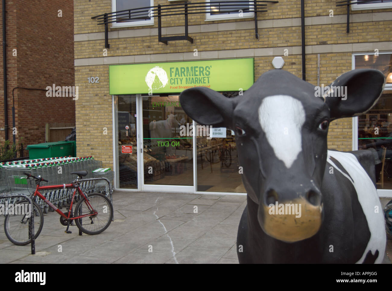 a cow statue stands in front of the entrance to farmers’ city market, a ...