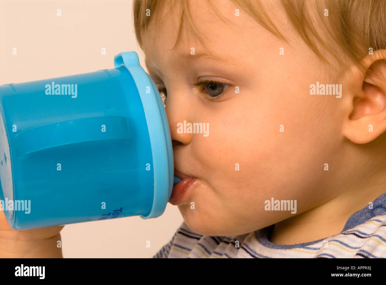 Baby boy eleven months old holding his own drinking cup with a spout ...