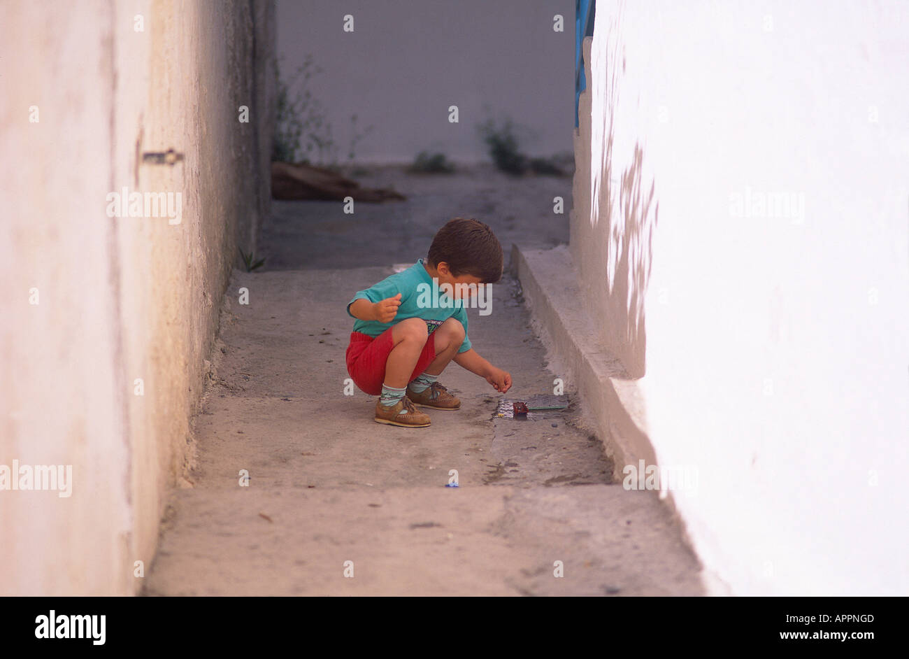 Small child crouched down and playing with a toy in a narrow stepped ...