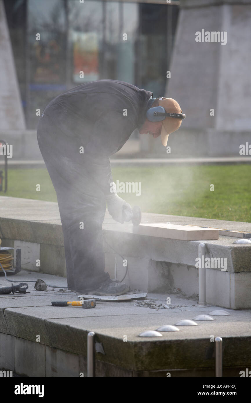 man cutting stone with an angle grinder repairing pedestrian area of ...