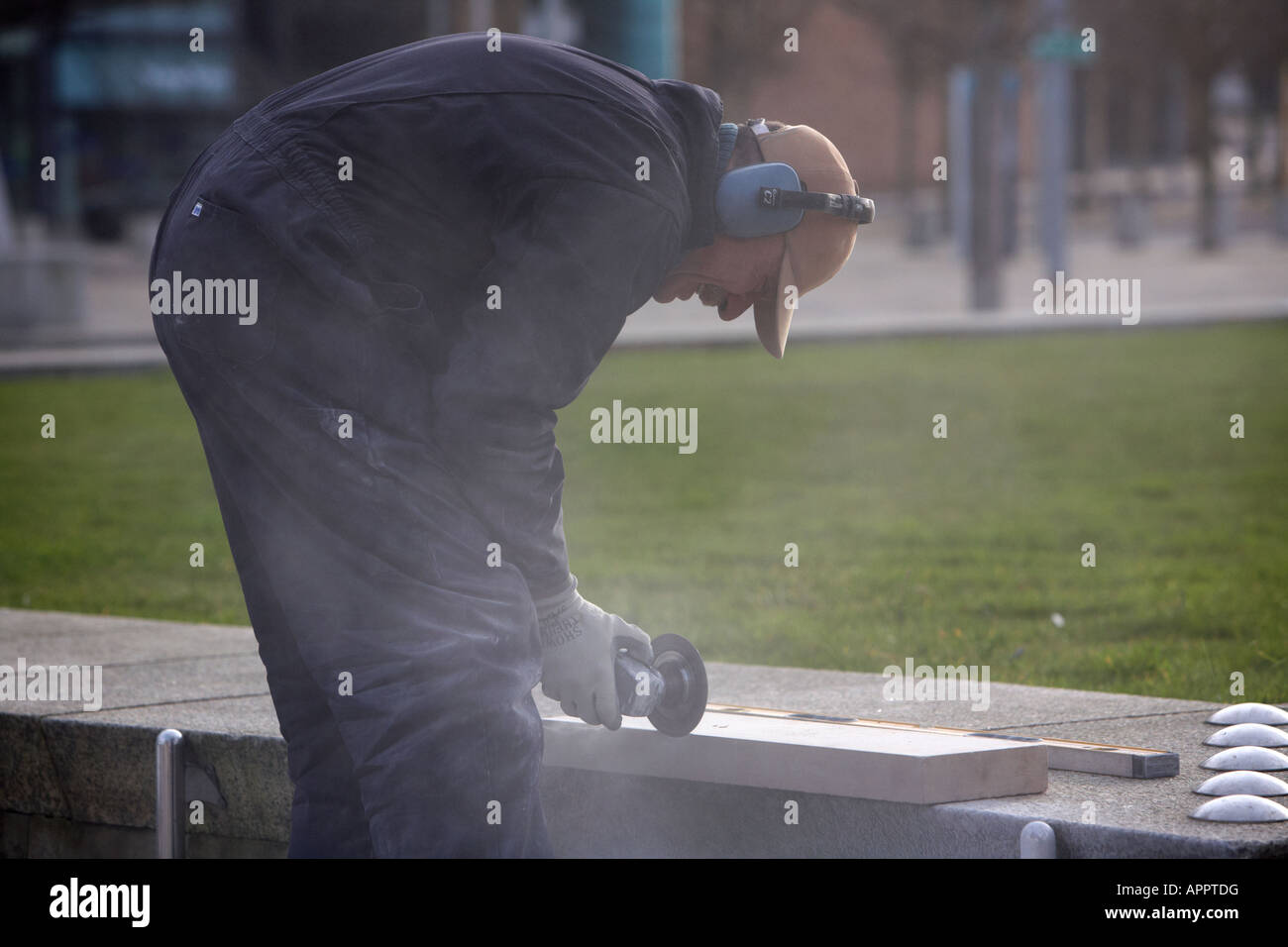 man cutting stone with an angle grinder repairing pedestrian area of ...