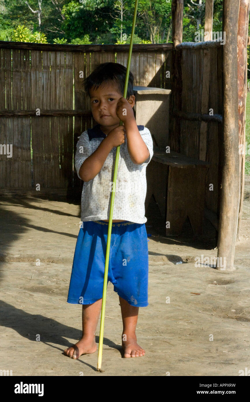 Ecuadorian young boy white Tshirt blue shorts, facing, holding bamboo ...