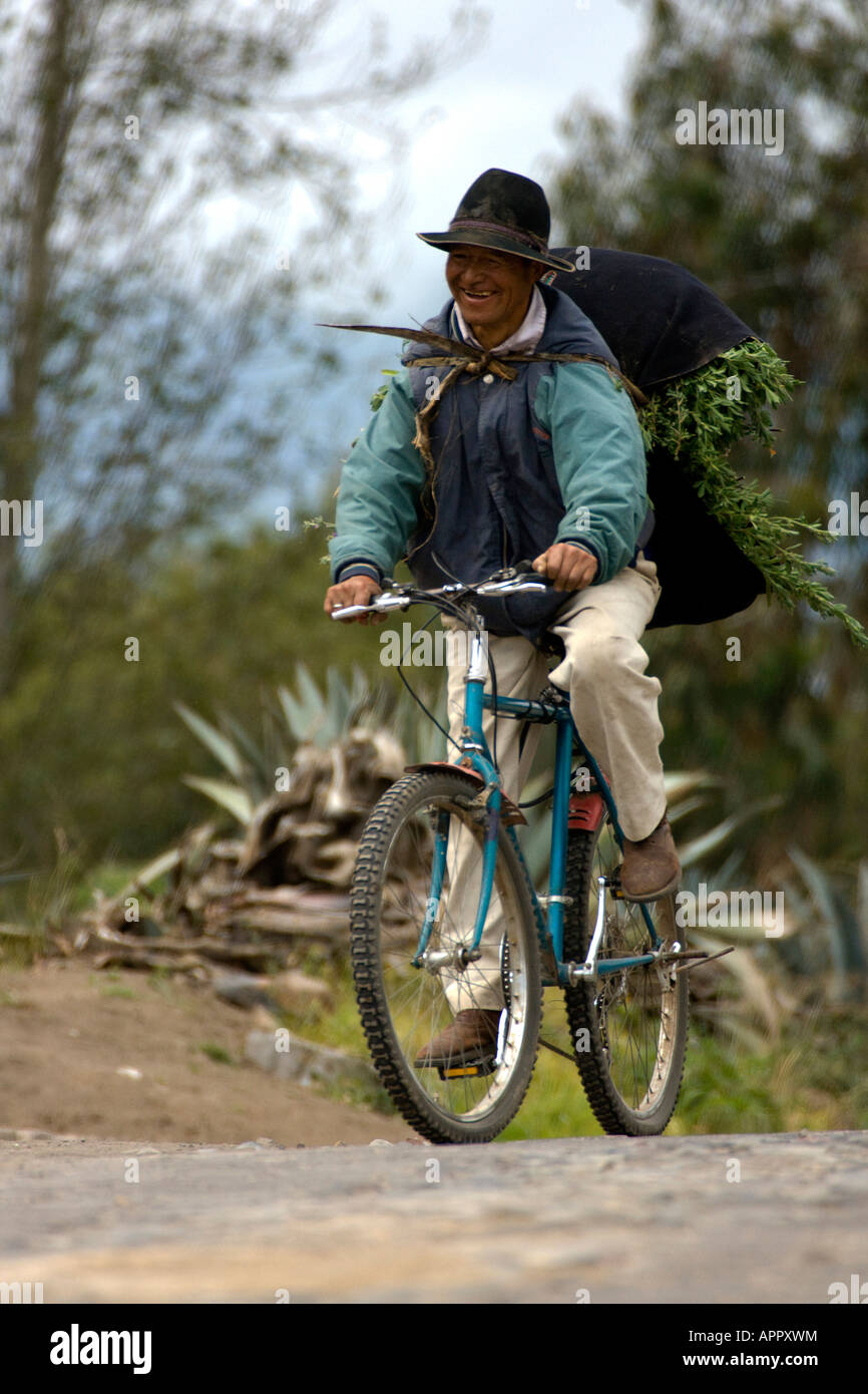 Ecuadorian man on bicycle, smiling, carrying heavy load on his back ...