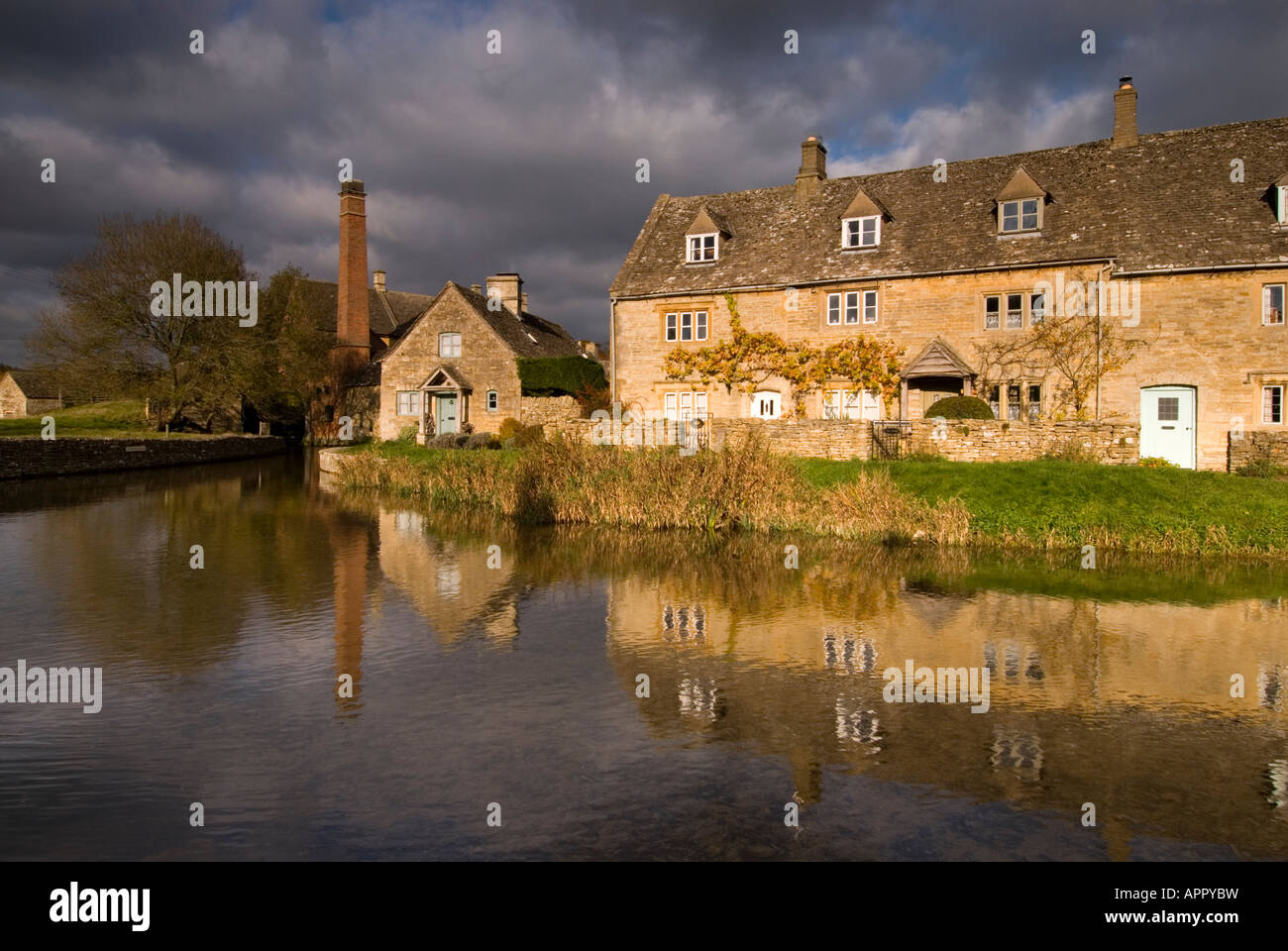 Row of Cotswold cottages and Water Mill Museum reflected in the River ...