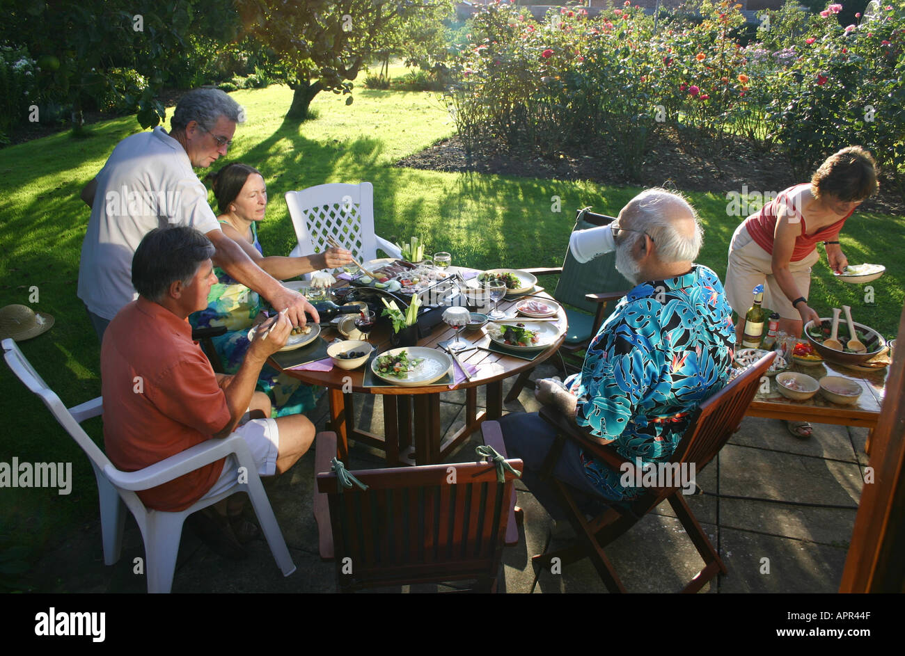 A group of friends having dinner in an English country garden in the UK ...