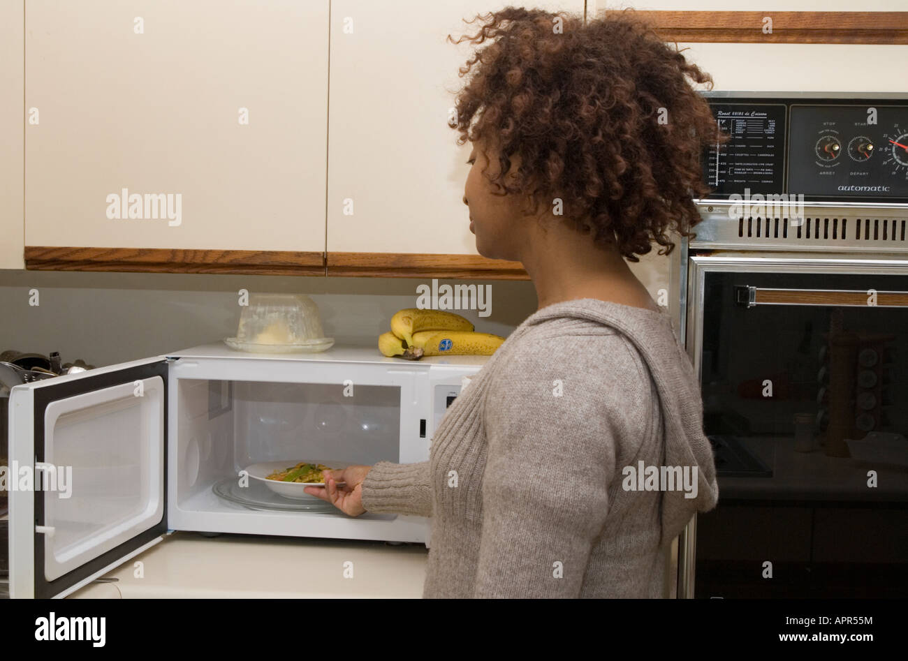 Woman using microwave Stock Photo - Alamy