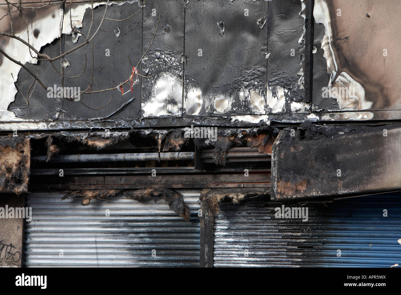melted facade and signs over metal shutters of fire damaged shop in ...