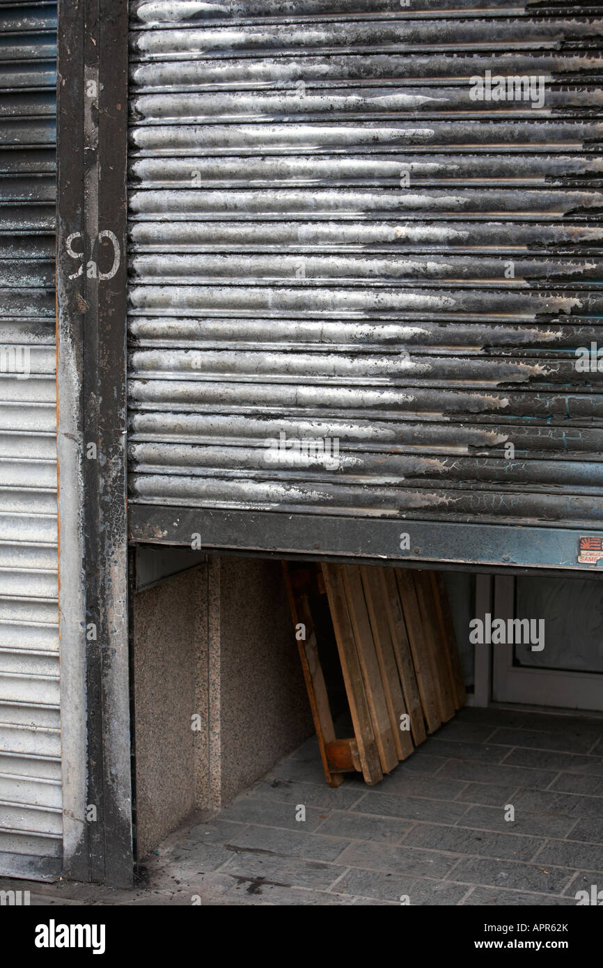 fire damaged metal security shutter at entrance to shop in city centre ...