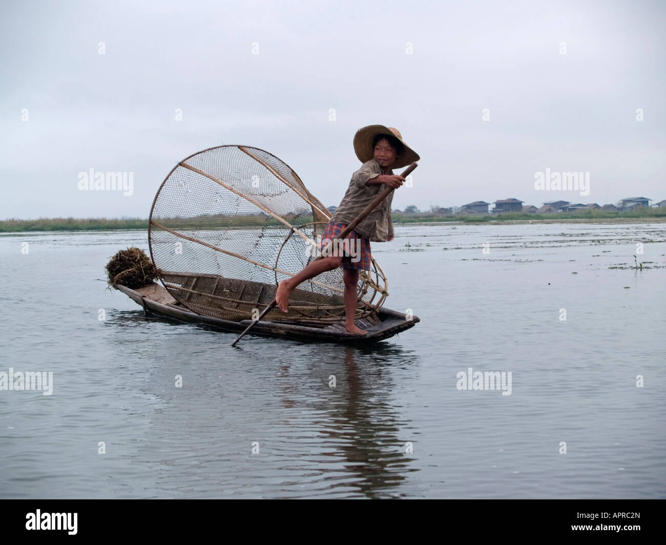 boy rowing with one leg on Inle Lake in Myanmar in order to free his ...