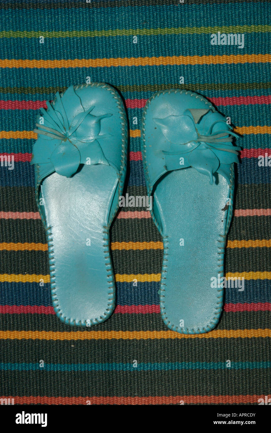 Bright turquoise sandals resting on a colorful striped mat in a cozy ...