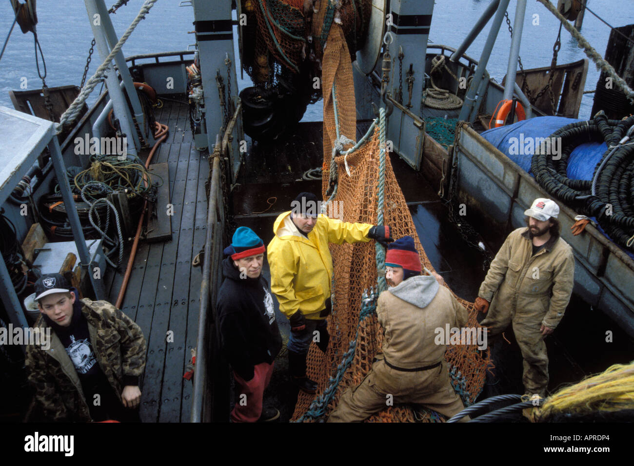 commercial fisherman fix a net on a small factory trawler as they hide ...