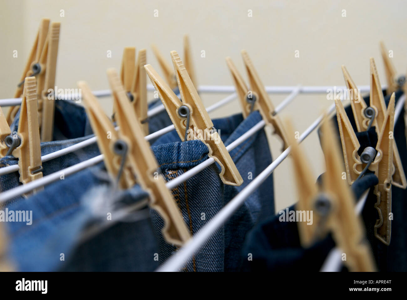 Denim jeans are neatly hung on a drying rack using clothespins. The ...