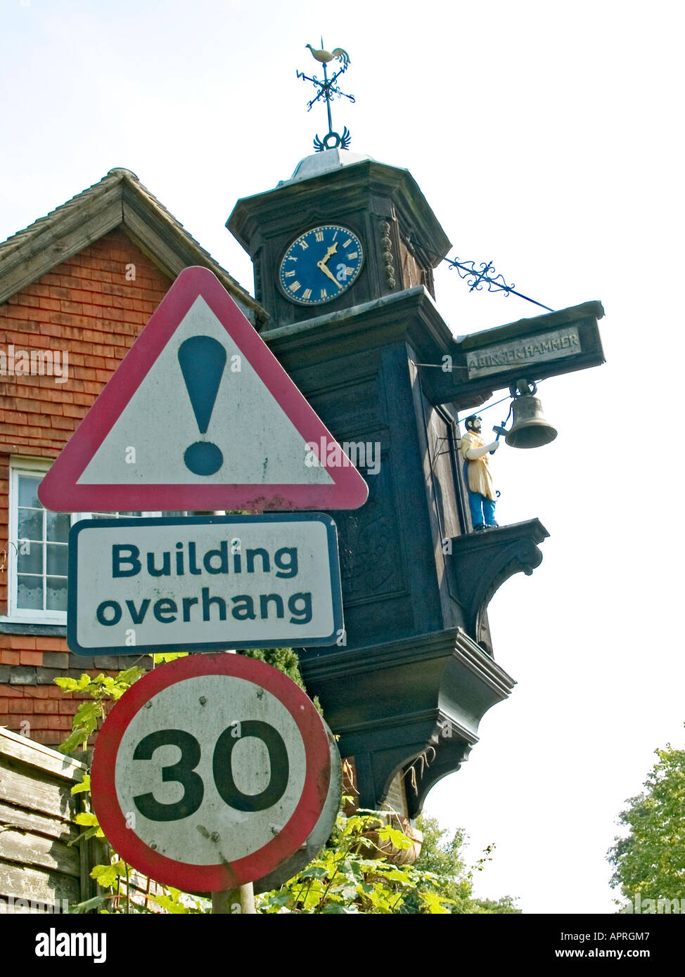 Warning signs for historic clock overhanging the road at Abinger Hammer ...