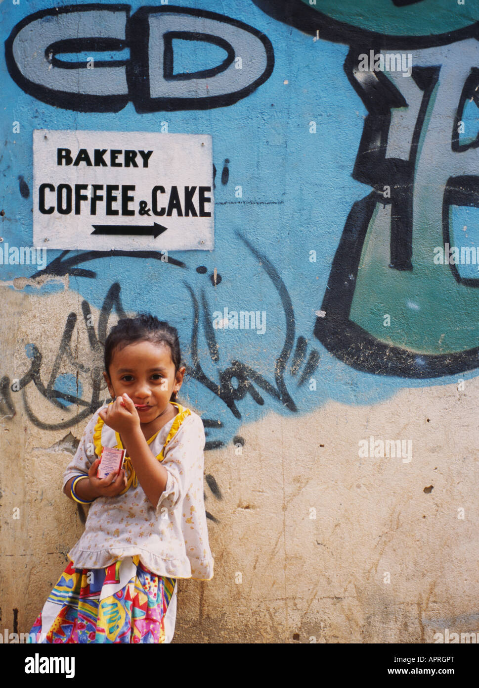 Asian girl eating under bakery sign Stock Photo - Alamy