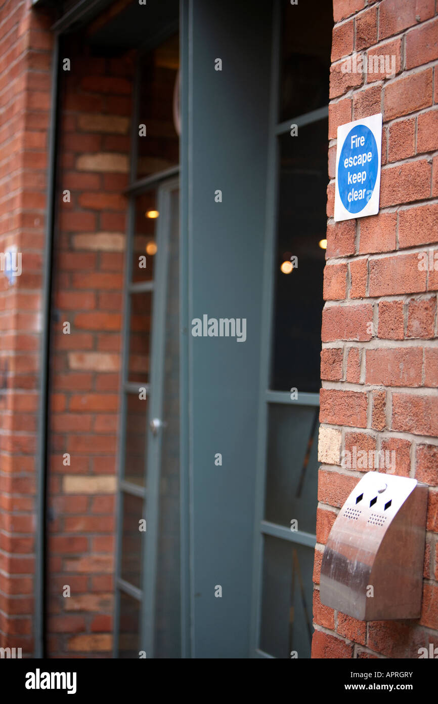 fire escape keep clear sign attached to red brick wall at entrance exit ...