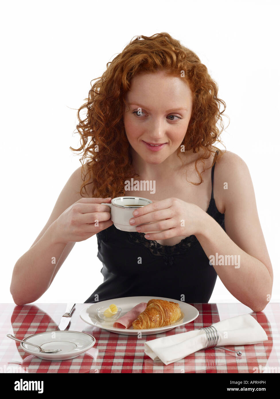 Young woman sitting at breakfast table croissant with ham and butter ...