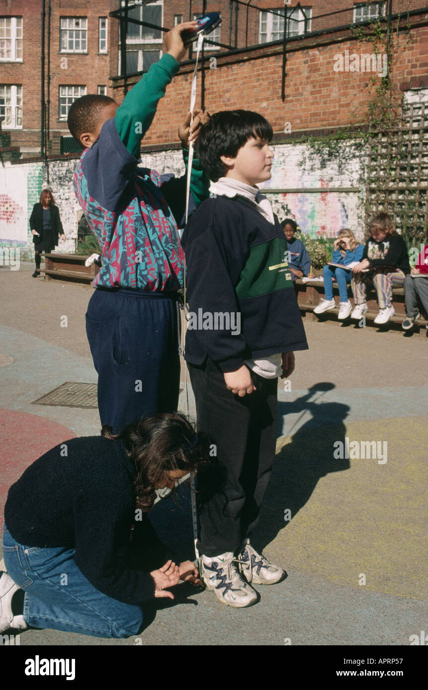 primary school children measuring their height in playground during a ...