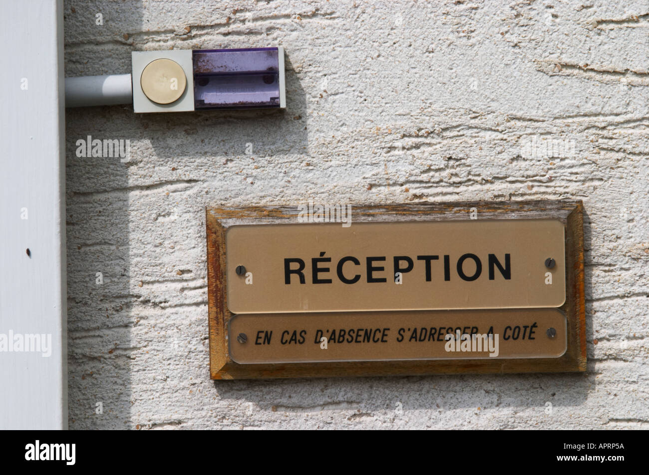 A door bell and sign saying reception, please call next door if no one ...
