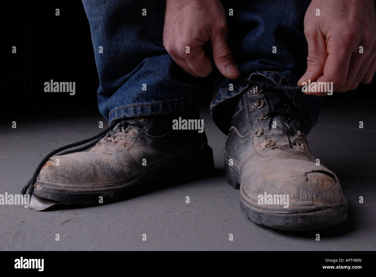 Workman tying old boot laces Stock Photo - Alamy