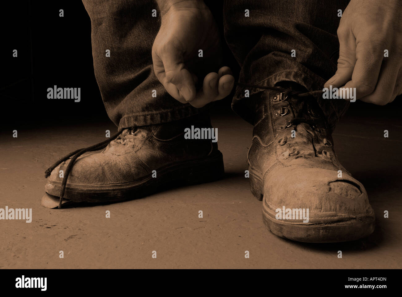 Workman tying old boot laces Stock Photo - Alamy