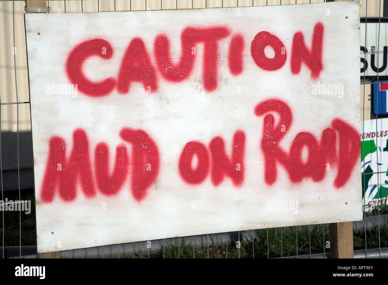 Red lettering sign Caution Mud on Road Stock Photo - Alamy
