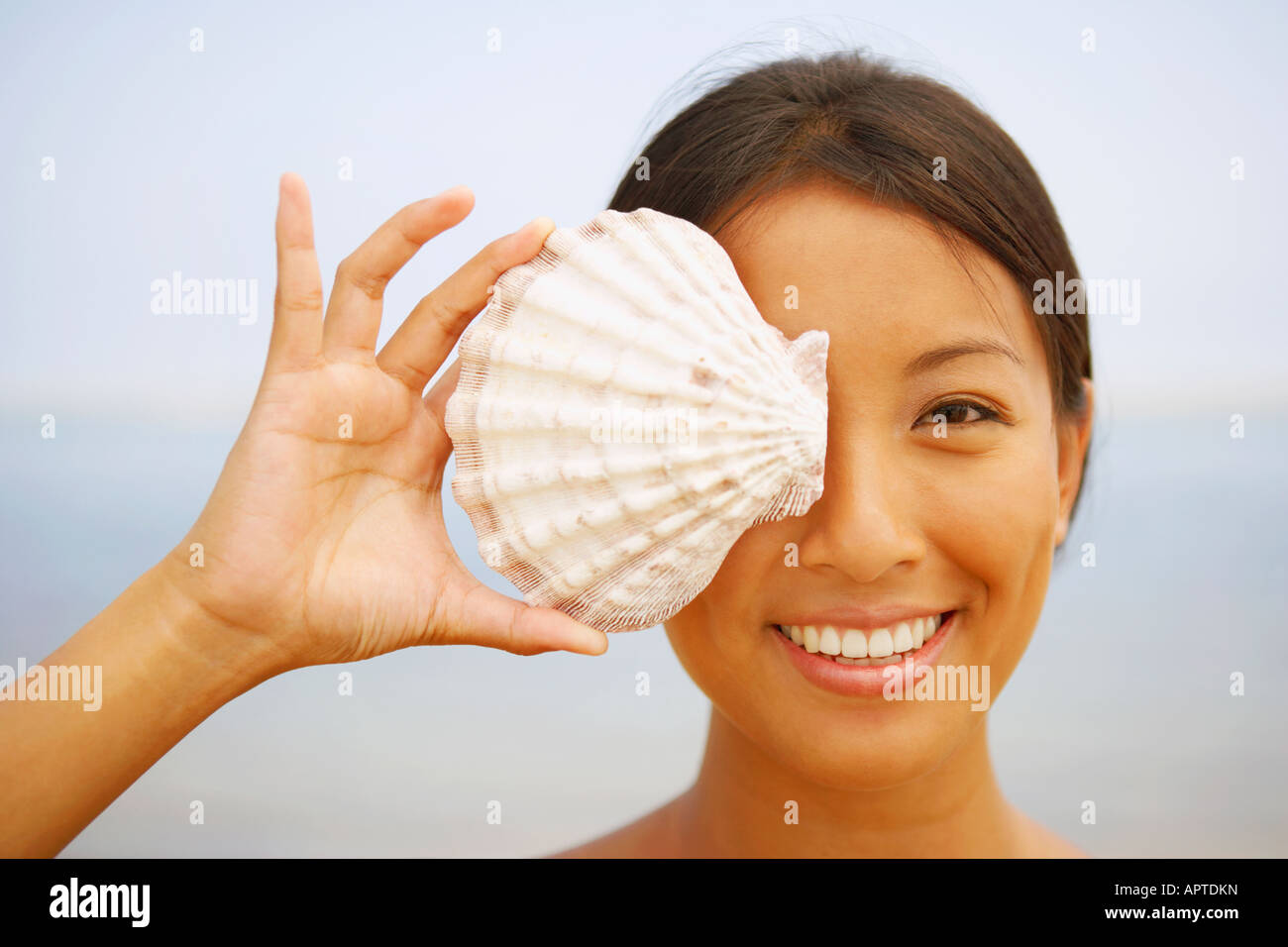 Asian woman holding seashell over eye Stock Photo - Alamy