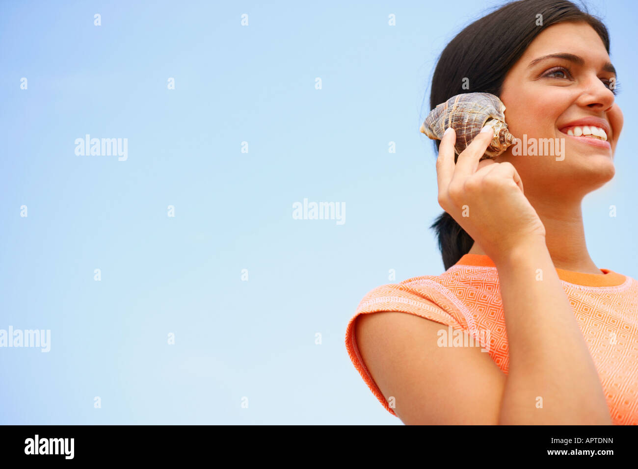 Woman listening to seashell Stock Photo - Alamy