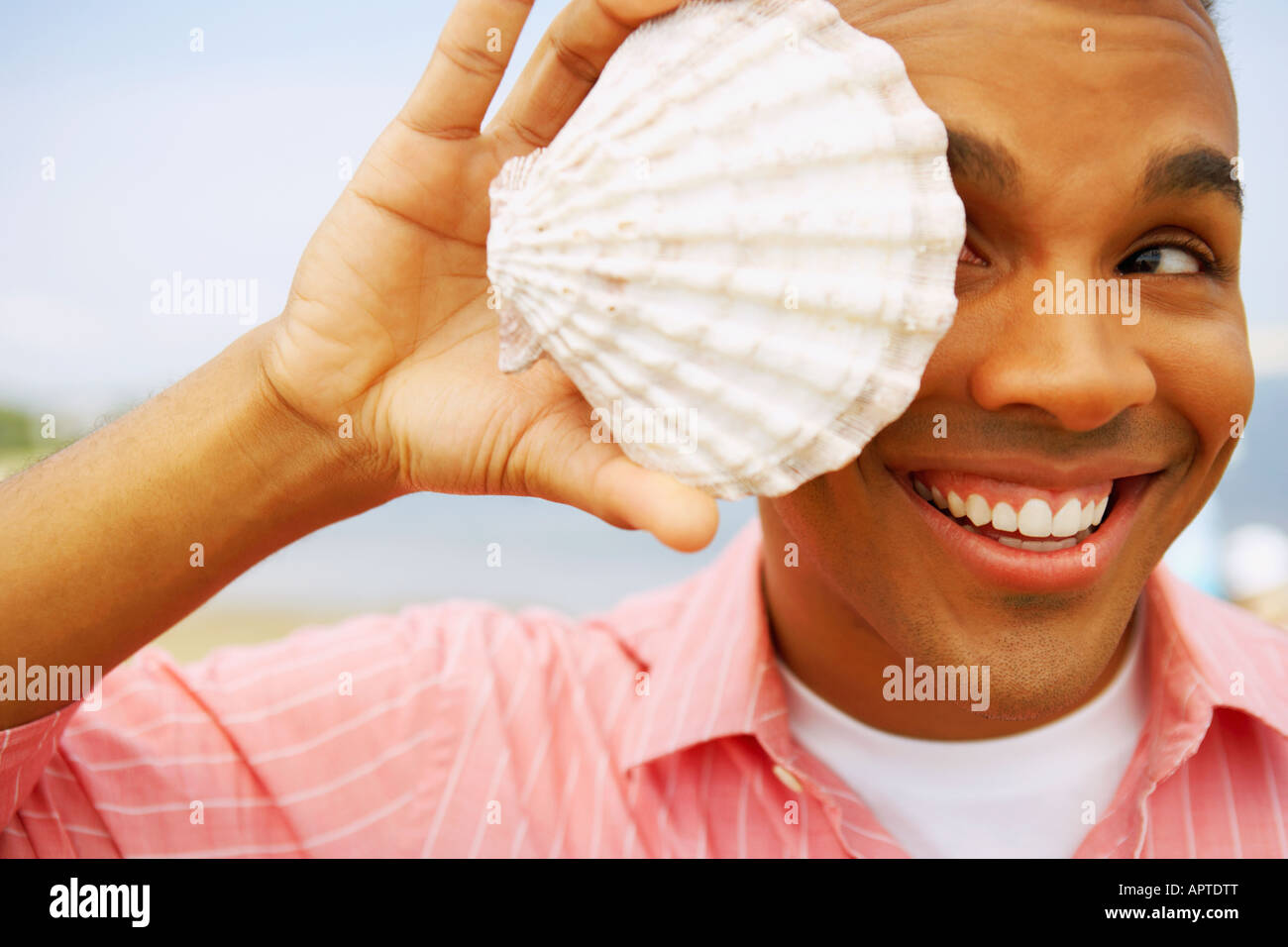 Hispanic man holding seashell over eye Stock Photo - Alamy