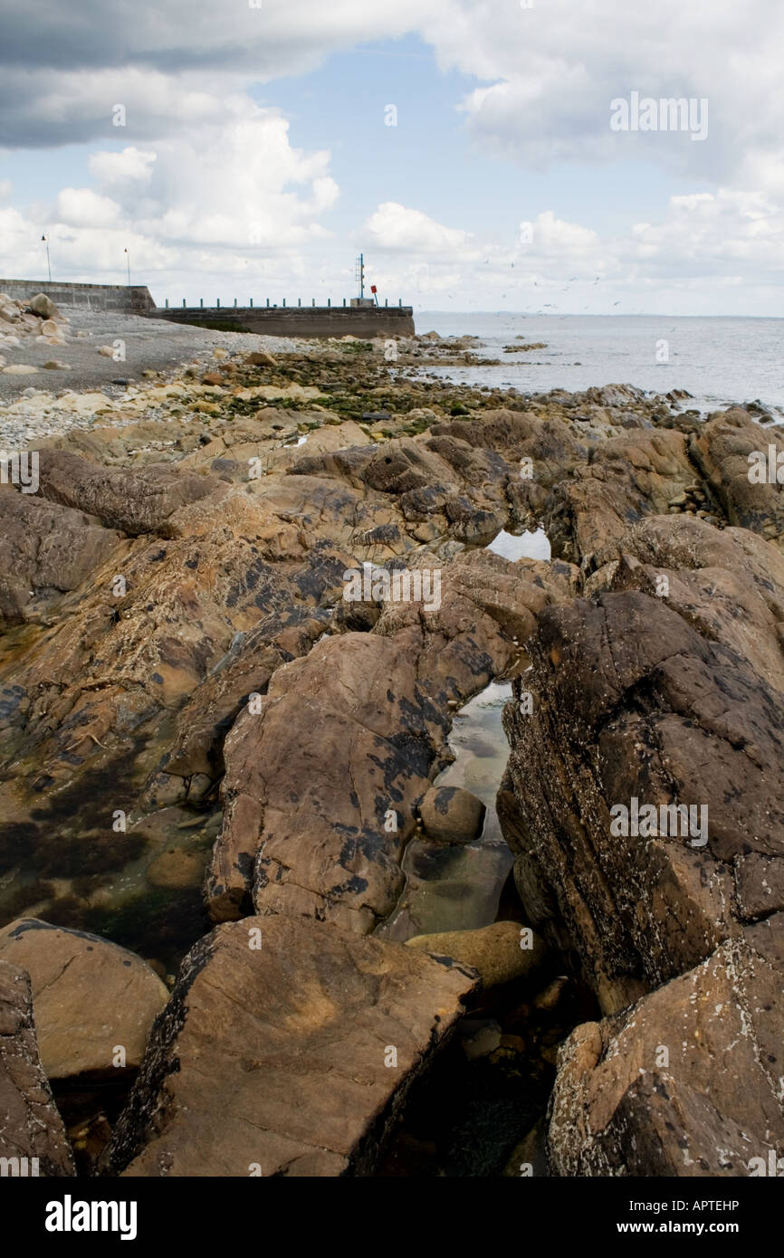 Rocky beach in Annalong looking towards the harbour pier Stock Photo ...