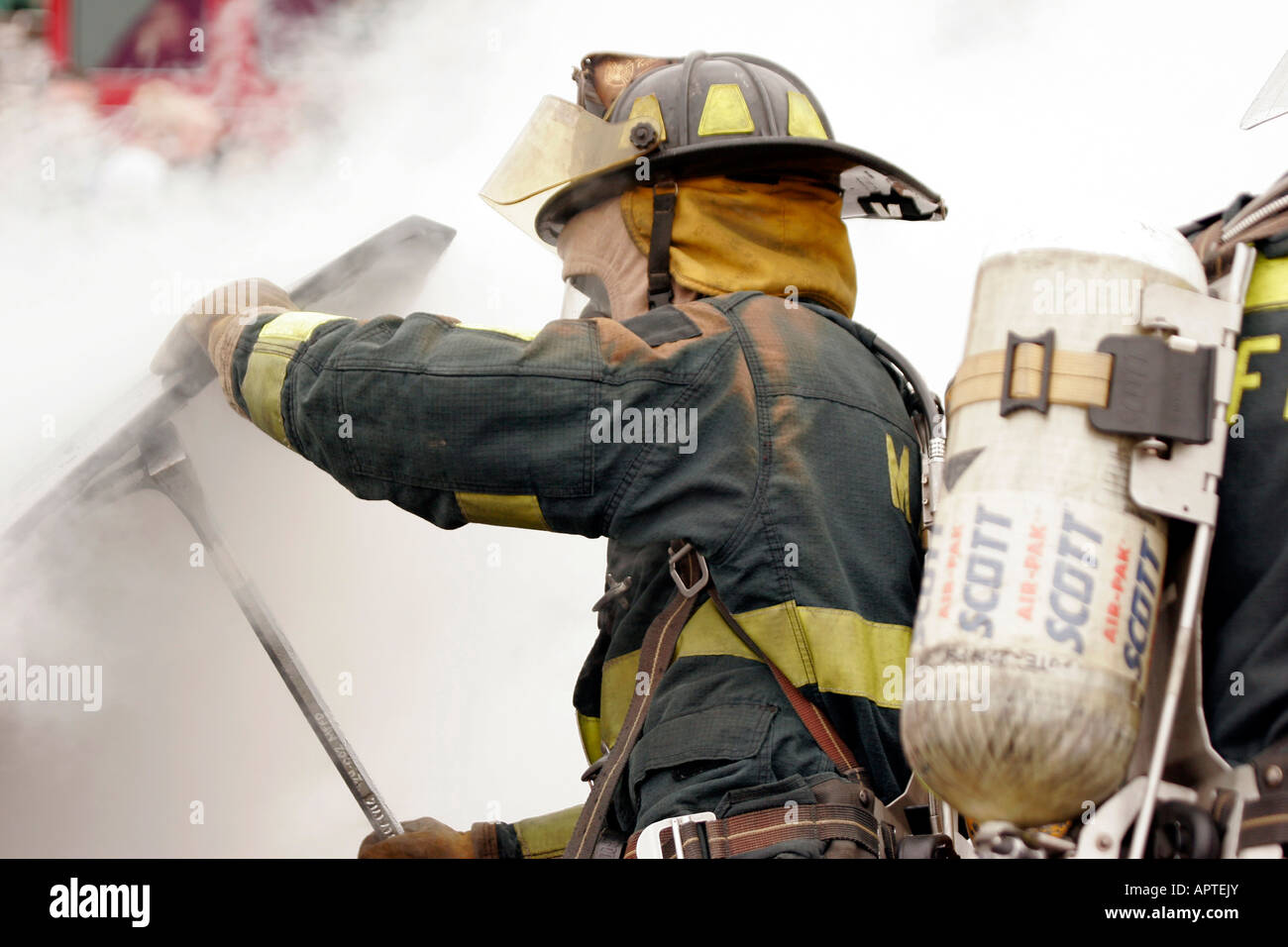 A firefighter propping up the hood to extinguish a car fire in the auto ...
