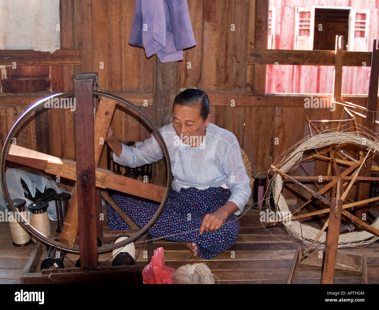 old woman spinning lotus threads into silk which is a cottage industry ...