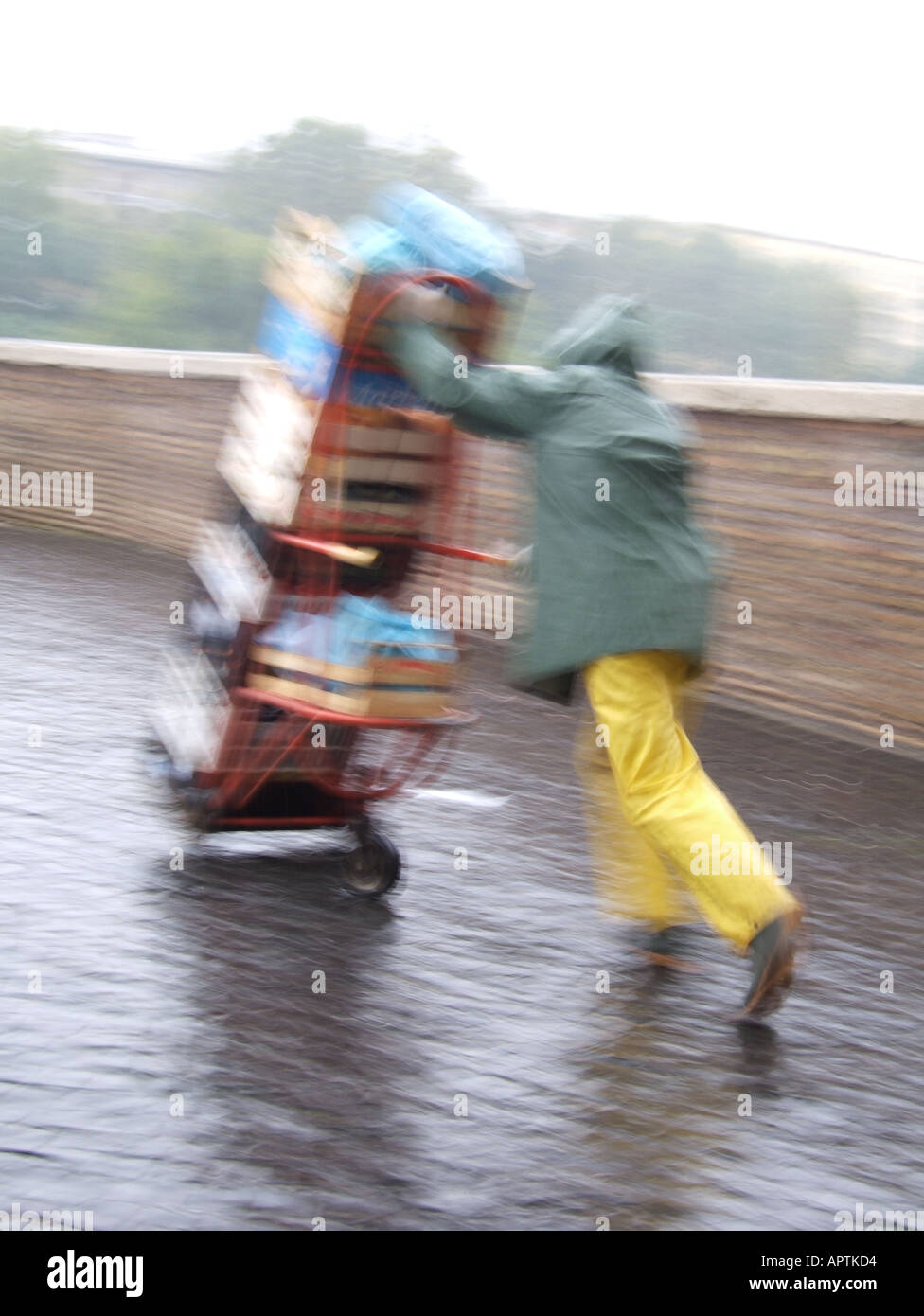 worker pushing heavy trolley in rain Stock Photo - Alamy