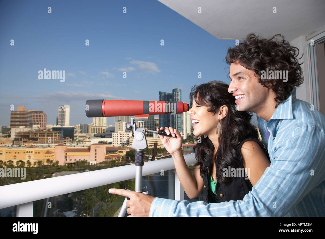 Hispanic couple looking through telescope on balcony Stock Photo - Alamy