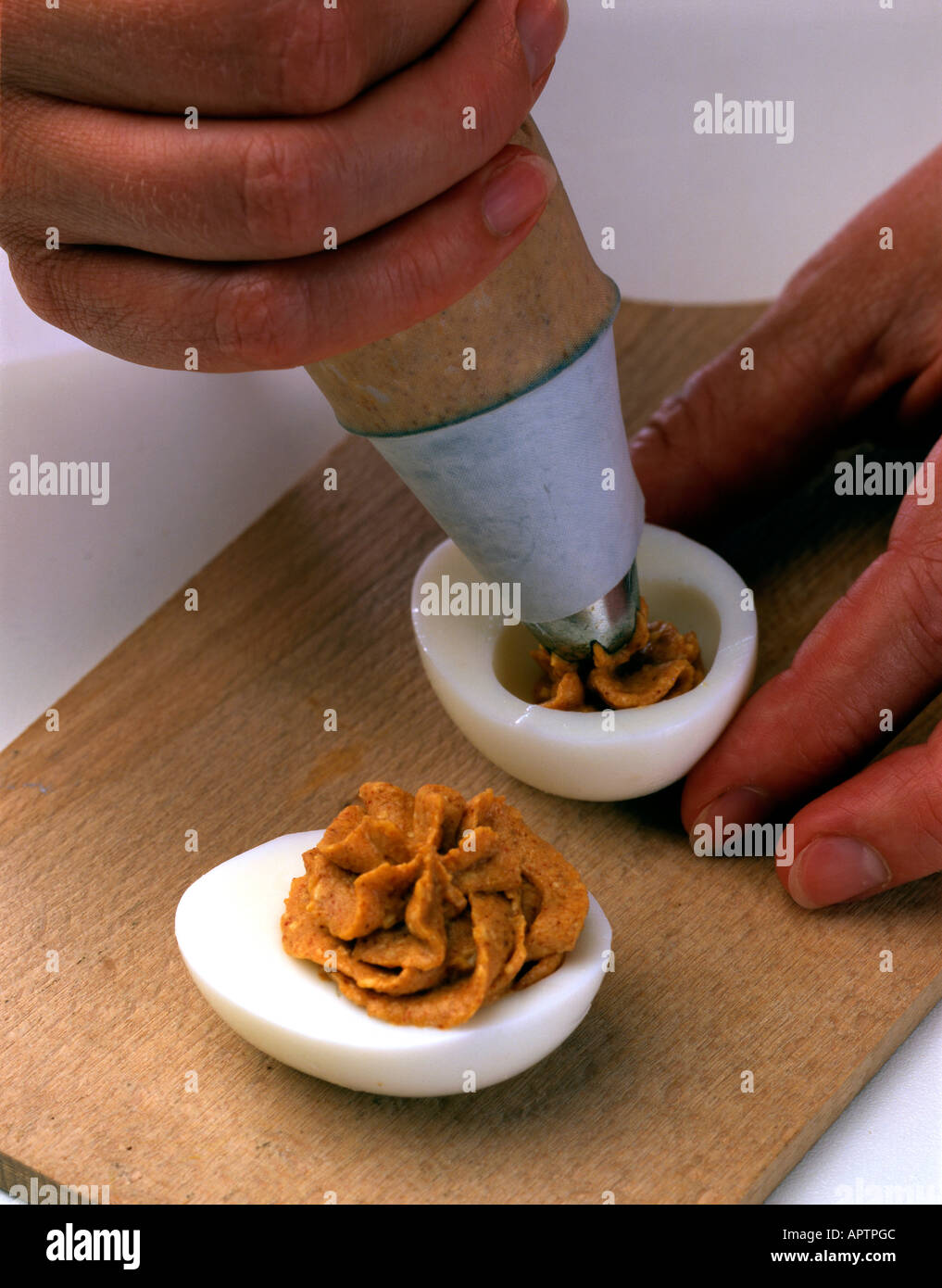 Stuffed hard boiled eggs - piping tuna tomato filling into centre of ...