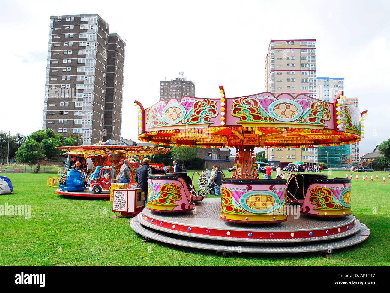 Fairground merry go round rides set against high rise apartment blocks ...