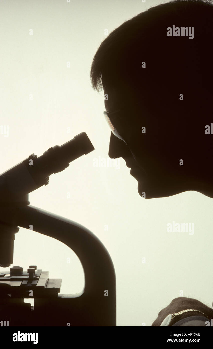 silhouette of lab technician looking through microscope Stock Photo - Alamy