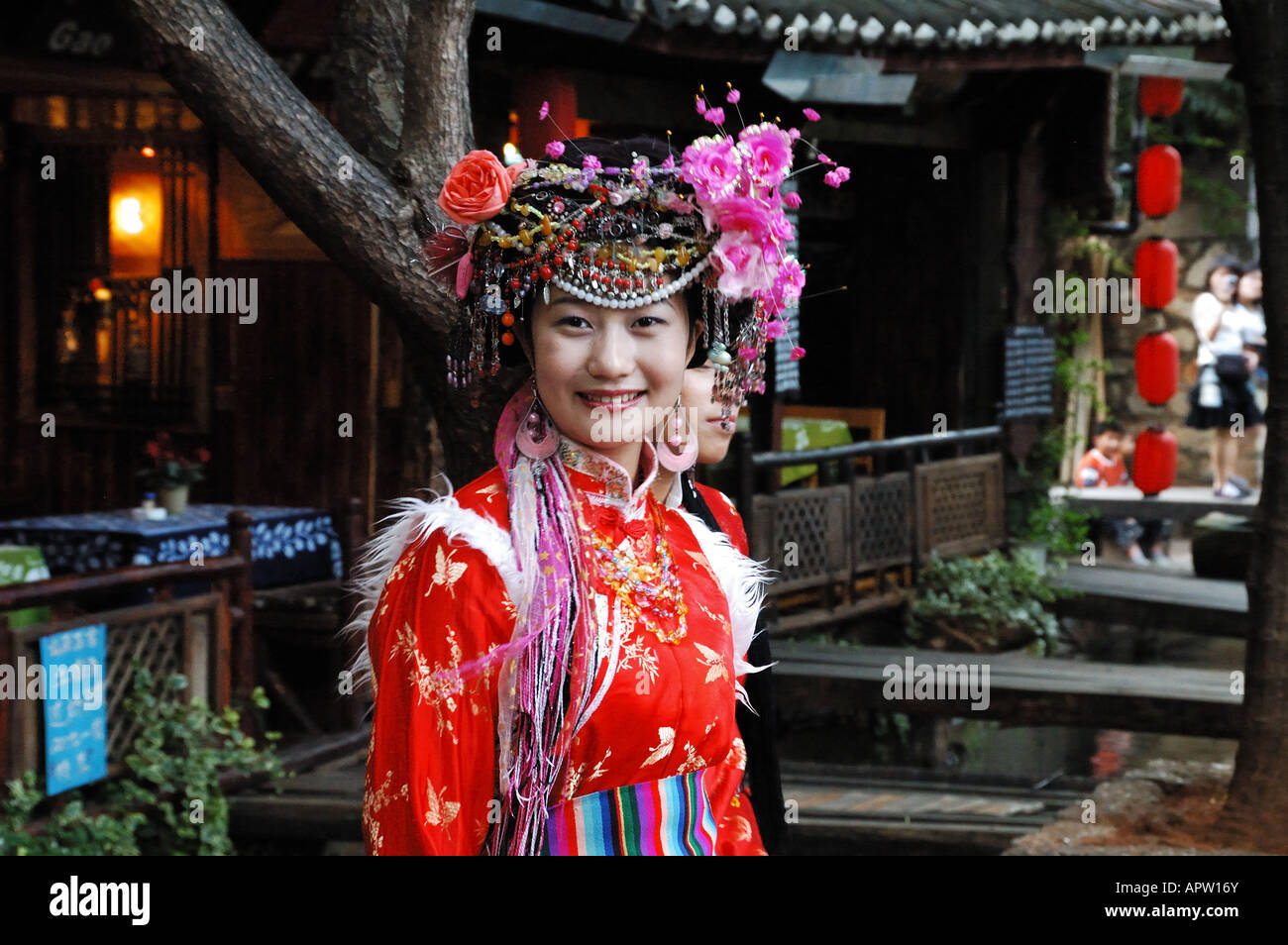 A young lady in traditional Naxi dress greets people with a bright ...
