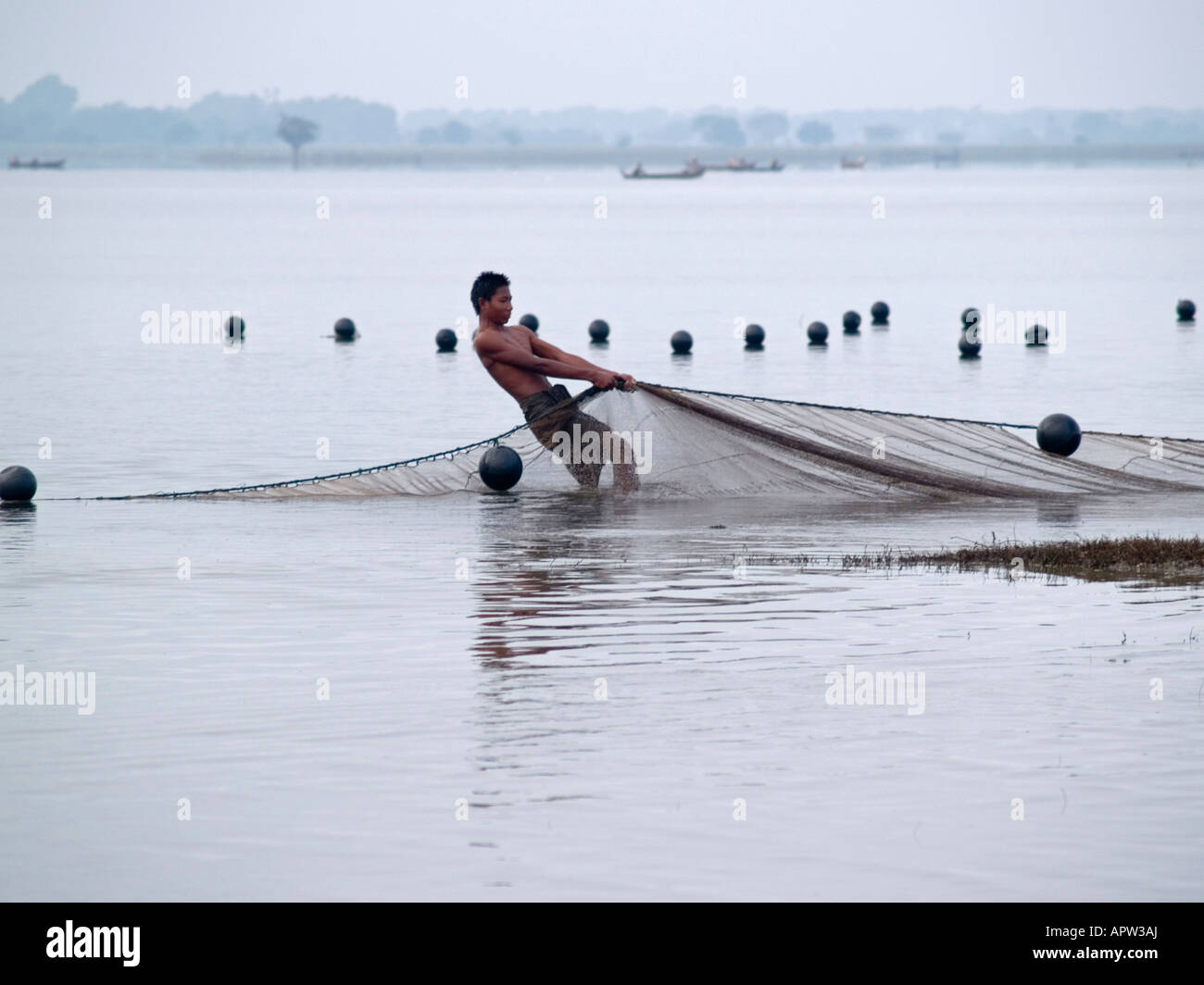 Burmese young man pulling in the fishing nets Stock Photo - Alamy