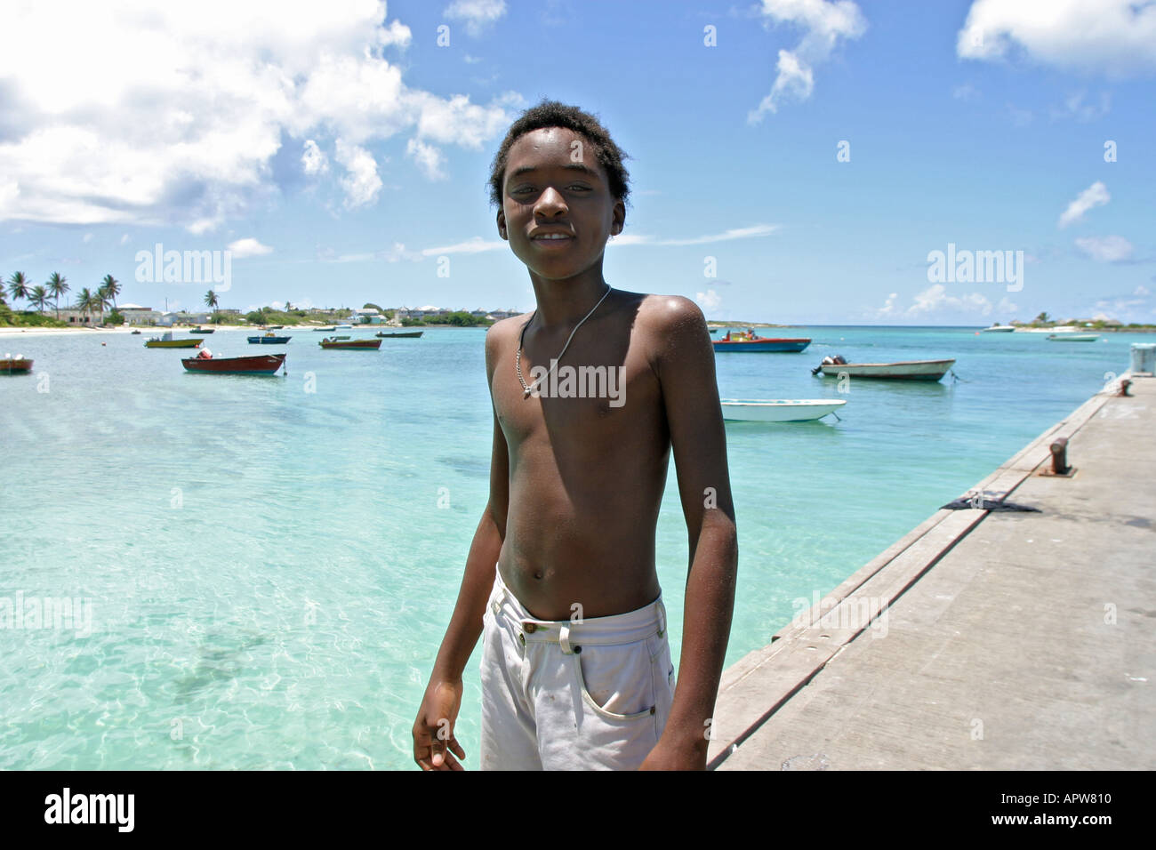 Boy standing on a jetty in Island Harbour in the caribbean sea off ...