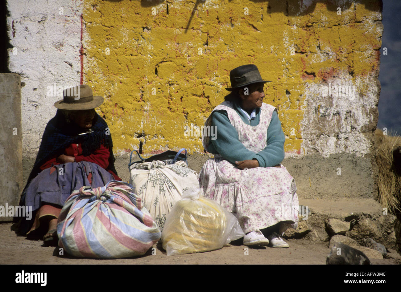 Two Aymara indian women waiting for the bus with their luggage. Peru ...