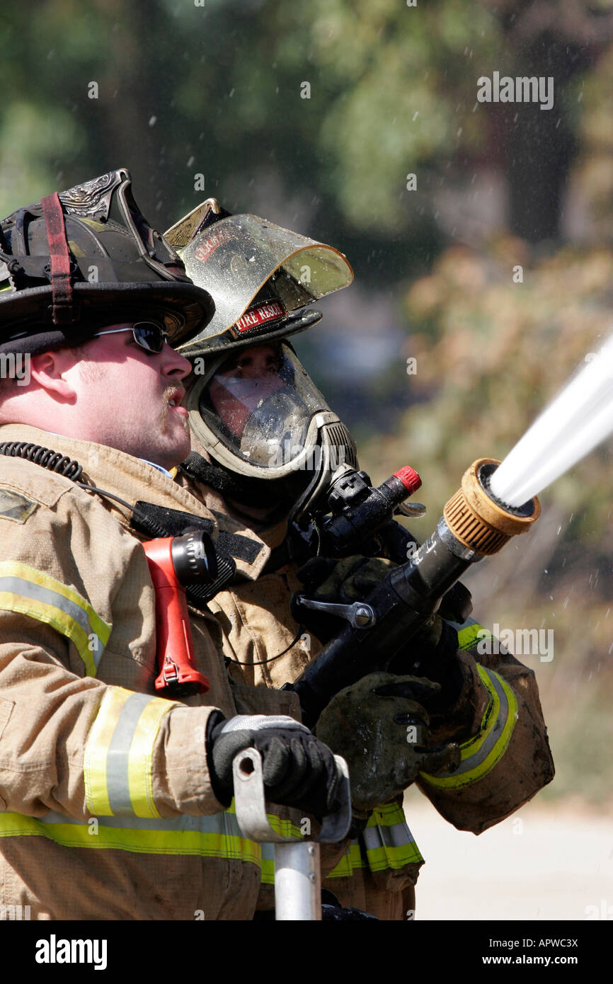 An American firefighter on a hoseline pumping and spraying water onto a ...