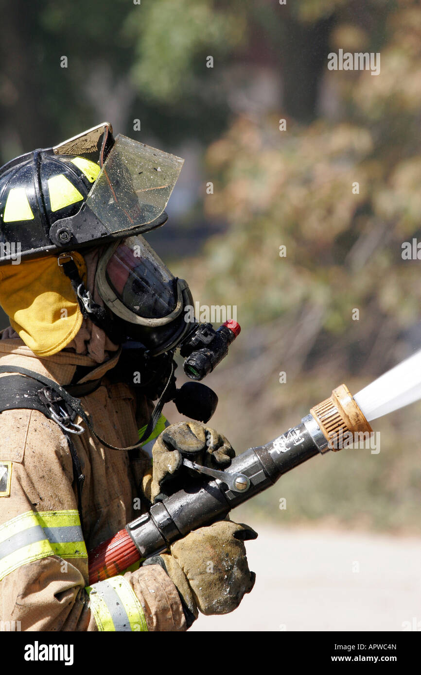 An American firefighter on a hoseline pumping and spraying water onto a ...